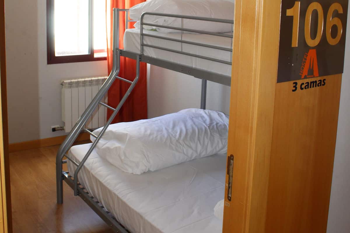 Quarto com beliche e porta de madeira com a inscrição '106 3 camas'.