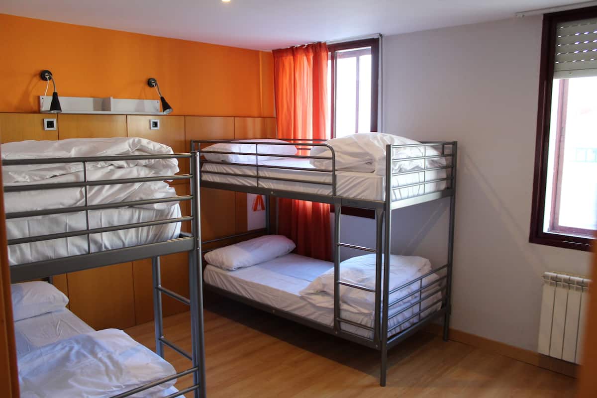 Quarto com beliches, piso de madeira e paredes laranja.