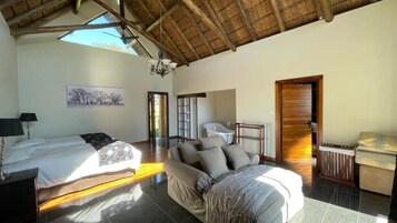 Quarto com duas camas, teto de madeira, lustre, banheira e porta de madeira.
