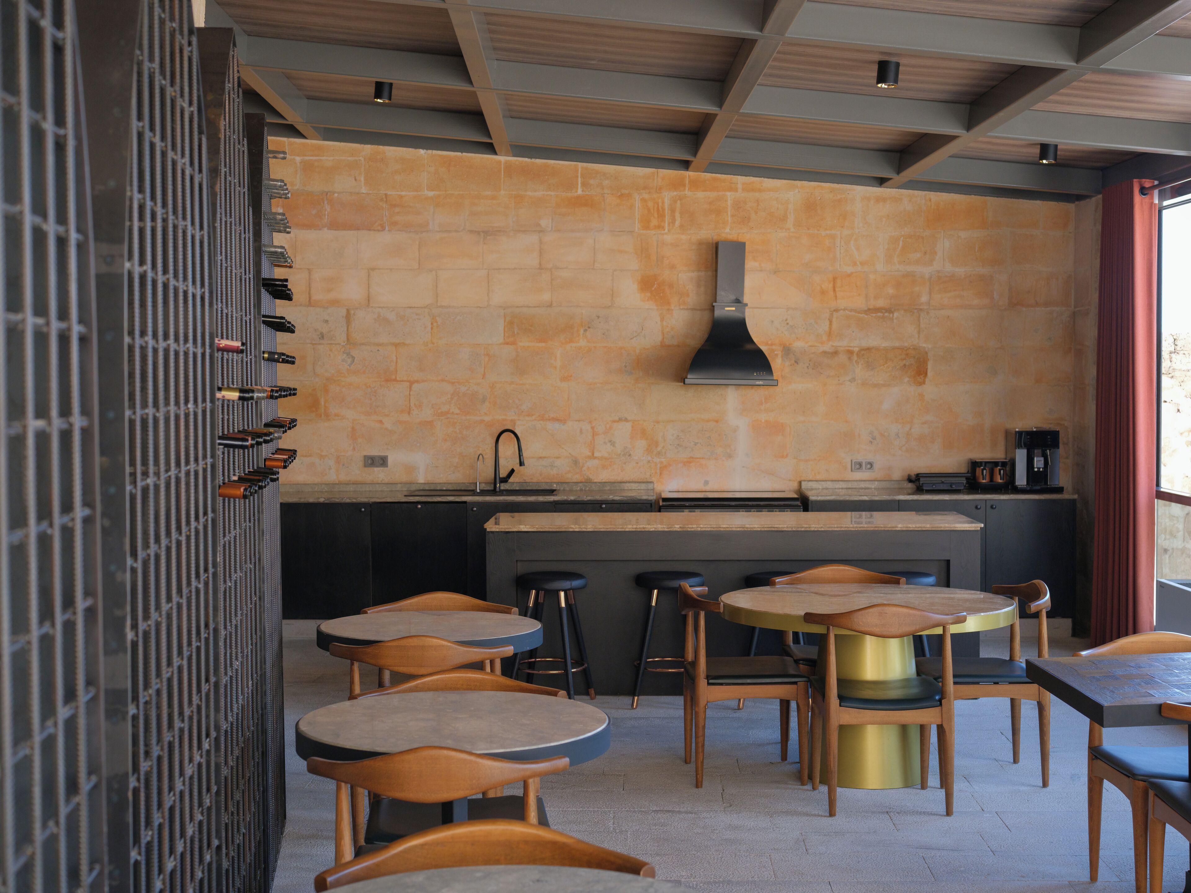 Cozinha moderna com painel de pedra, mesas de madeira e banquetas.