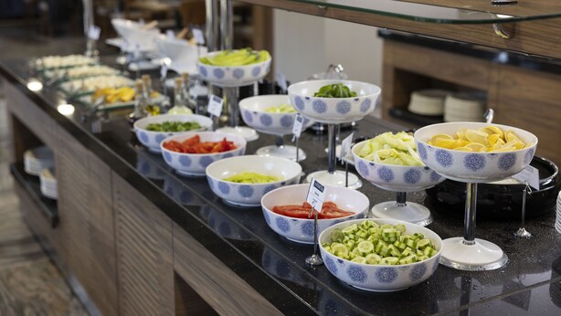 Buffet com diversos alimentos em tigelas, incluindo saladas e frutas.