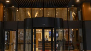 Entrada de um hotel com uma porta giratória e o nome "ANEMON" exibido acima.
