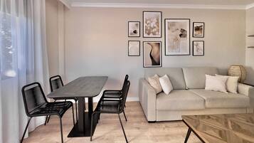 Uma sala de estar moderna com área de jantar, com um sofá, uma mesa de centro e uma mesa de jantar com cadeiras.
