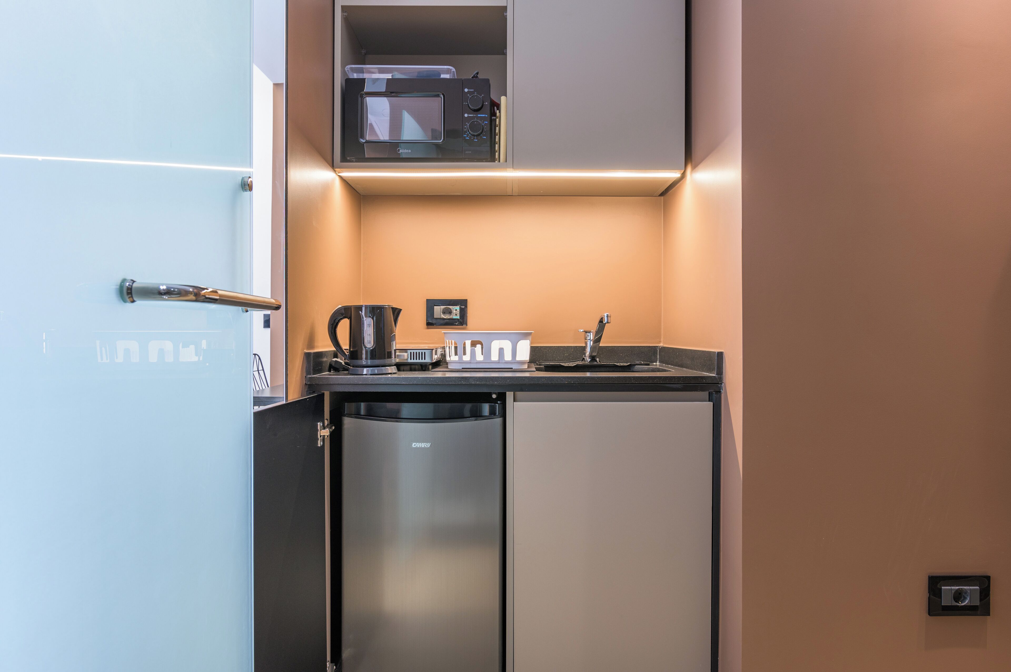 Cozinha compacta com micro-ondas, máquina de café e lava-louças.