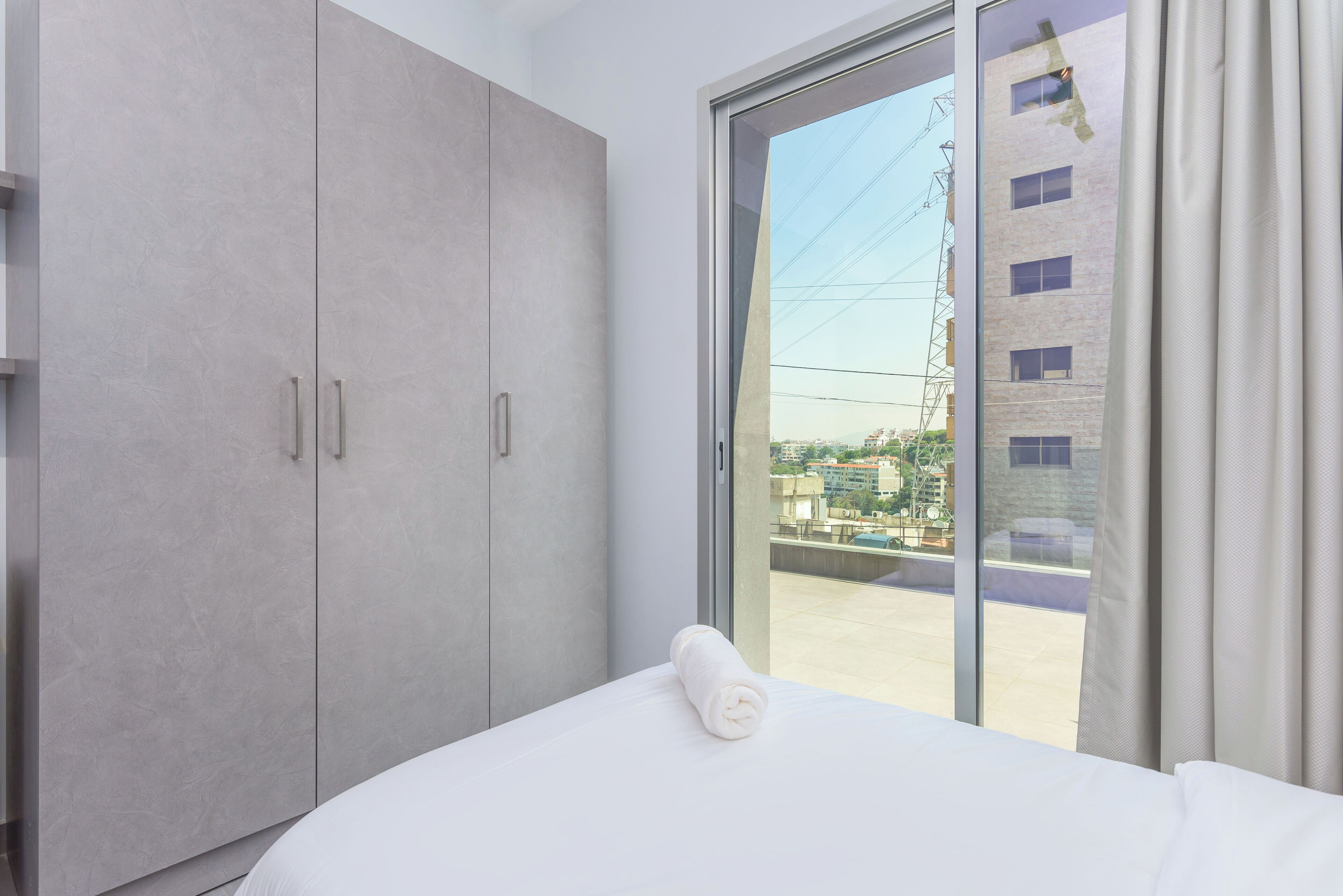 Quarto de hotel com uma cama, um guarda-roupa grande e uma porta de correr de vidro para o exterior.