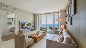 Uma sala de estar moderna com televisão, sofá, mesa de centro e vista para o mar.