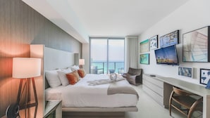 Quarto de hotel moderno com uma cama grande, uma escrivaninha e vista para a cidade.
