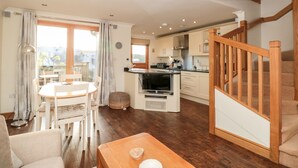 Cozinha moderna com ilha central, soalho em madeira e escada com grades de madeira.