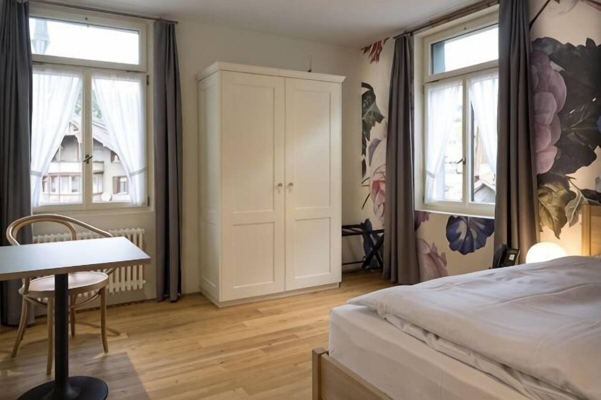Um quarto com uma cama, um guarda-roupa branco, uma mesa e uma cadeira.