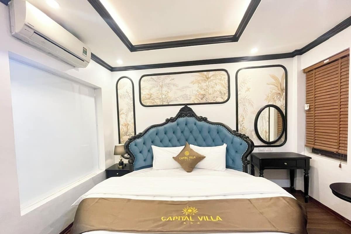 Quarto de hotel com uma cama, mesa de cabeceira, espelho e janela com persianas.