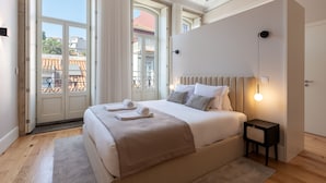 Quarto com uma cama grande, mesa de cabeceira e vista para o exterior.
