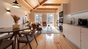 Uma cozinha moderna com vigas de madeira, uma sala de jantar com mesa de vidro e vista para a cidade através de amplas janelas.