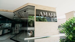 Um edifício moderno com entrada de vidro e uma placa com a inscrição "AMARI Living Suites".