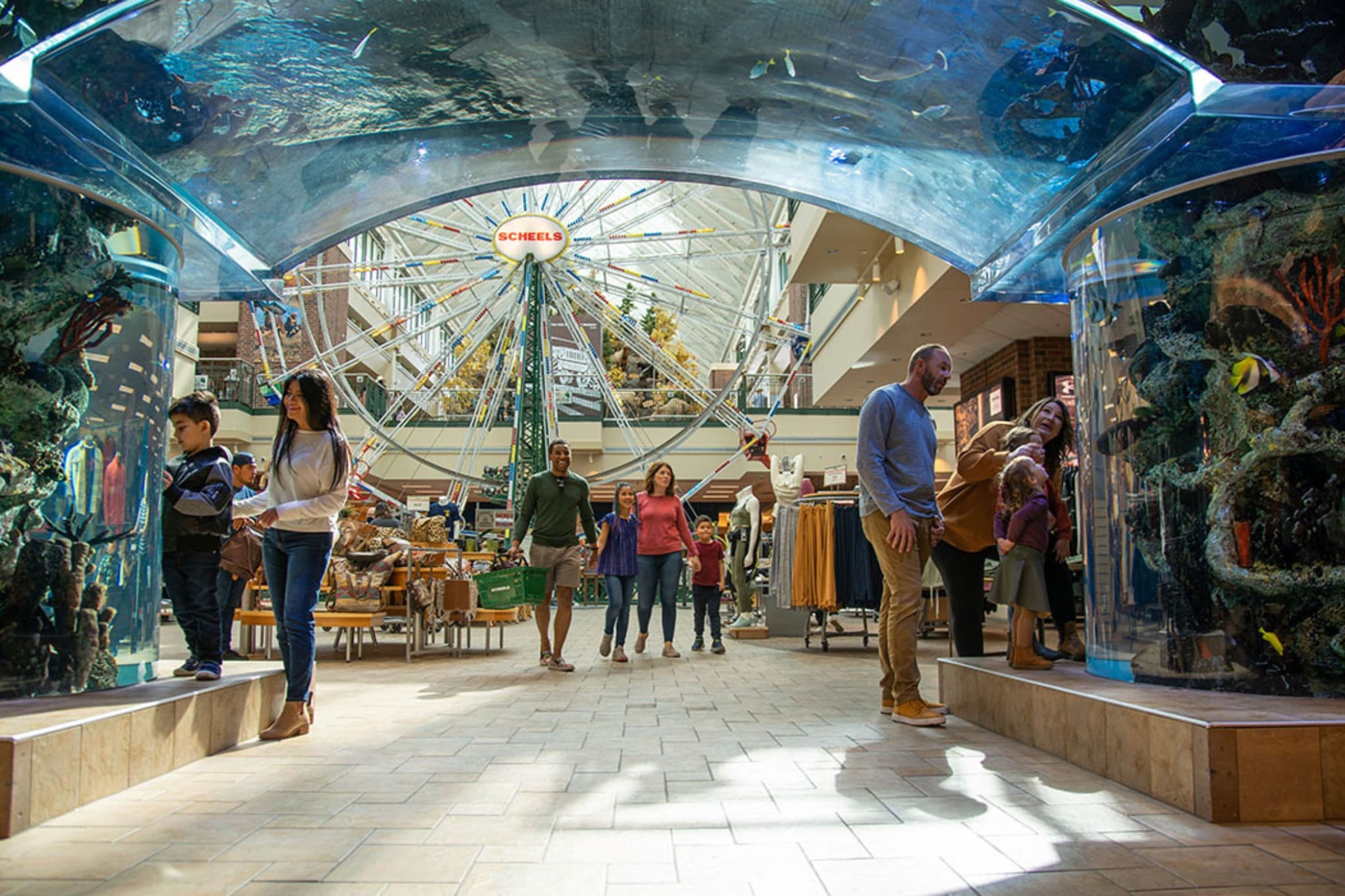 Um shopping center interno com uma roda gigante, aquários e diversas lojas.