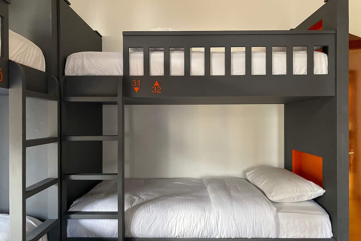 Uma cama beliche com dois níveis, cada um com colchão e travesseiros.