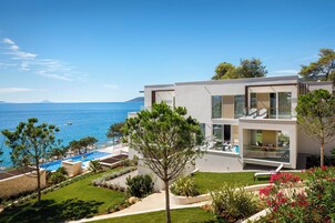 Um edifício moderno de dois andares com piscina e vista para o mar.