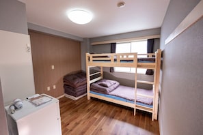 Quarto com beliche, iluminação no teto, piso de madeira e janela com cortinas.
