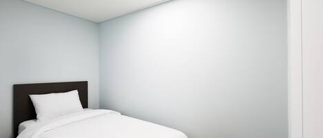 Quarto de hotel com uma cama, uma porta e uma luminária no teto.