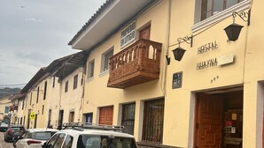 Rua com carros estacionados e um prédio com uma placa indicando "PROPIEDAD EN LITIGIO".