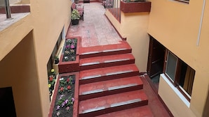 Um edifício com vários níveis, uma escadaria central, varandas e plantas em vasos.
