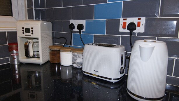 Uma cozinha com uma torradeira, uma cafeteira e potes sobre o balcão.