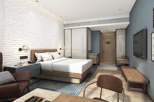 Quarto de hotel moderno com uma cama grande, uma escrivaninha, uma cadeira e uma televisão.