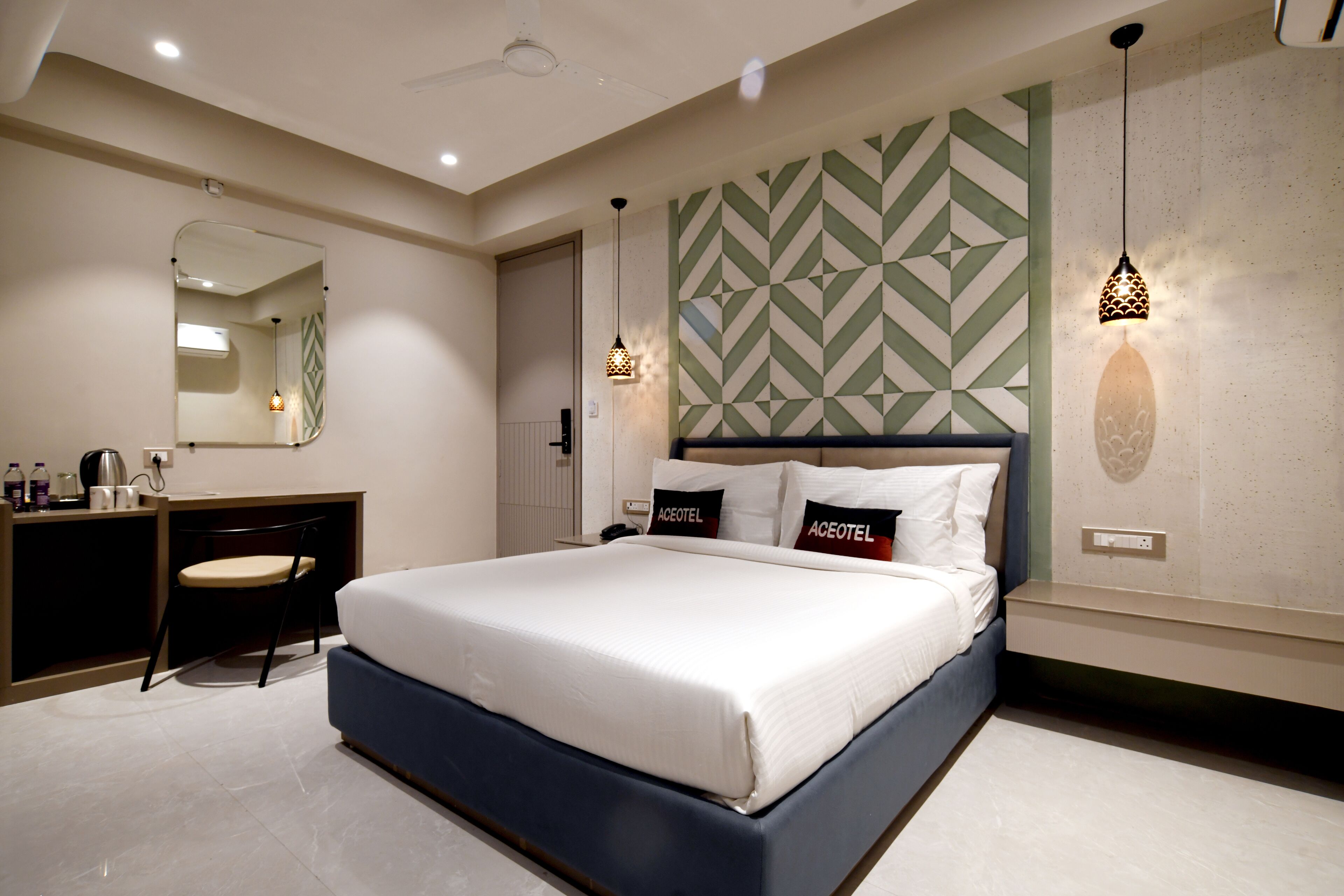 Quarto de hotel moderno com uma cama grande, uma mesa com cadeira e um espelho.