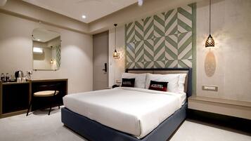 Quarto de hotel moderno com uma cama grande, uma mesa com cadeira e um espelho.