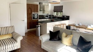 Uma cozinha moderna com ilha central, armários de madeira e um cesto de lixo de aço inoxidável.