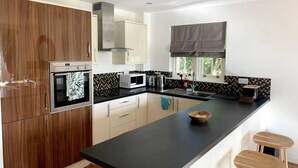 Uma cozinha moderna com armários de madeira, coifa de aço inoxidável, micro-ondas e uma ilha grande com banquetas.