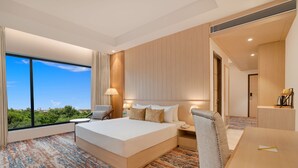Quarto de hotel moderno com uma cama grande, uma escrivaninha e vista para o exterior.
