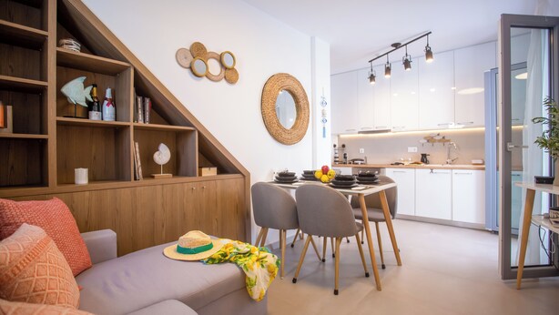 Uma sala de estar moderna com sofá, área de jantar, cozinha e escada.