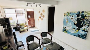 Uma sala de estar com sofá, duas poltronas, uma mesa de centro e um quadro na parede.
