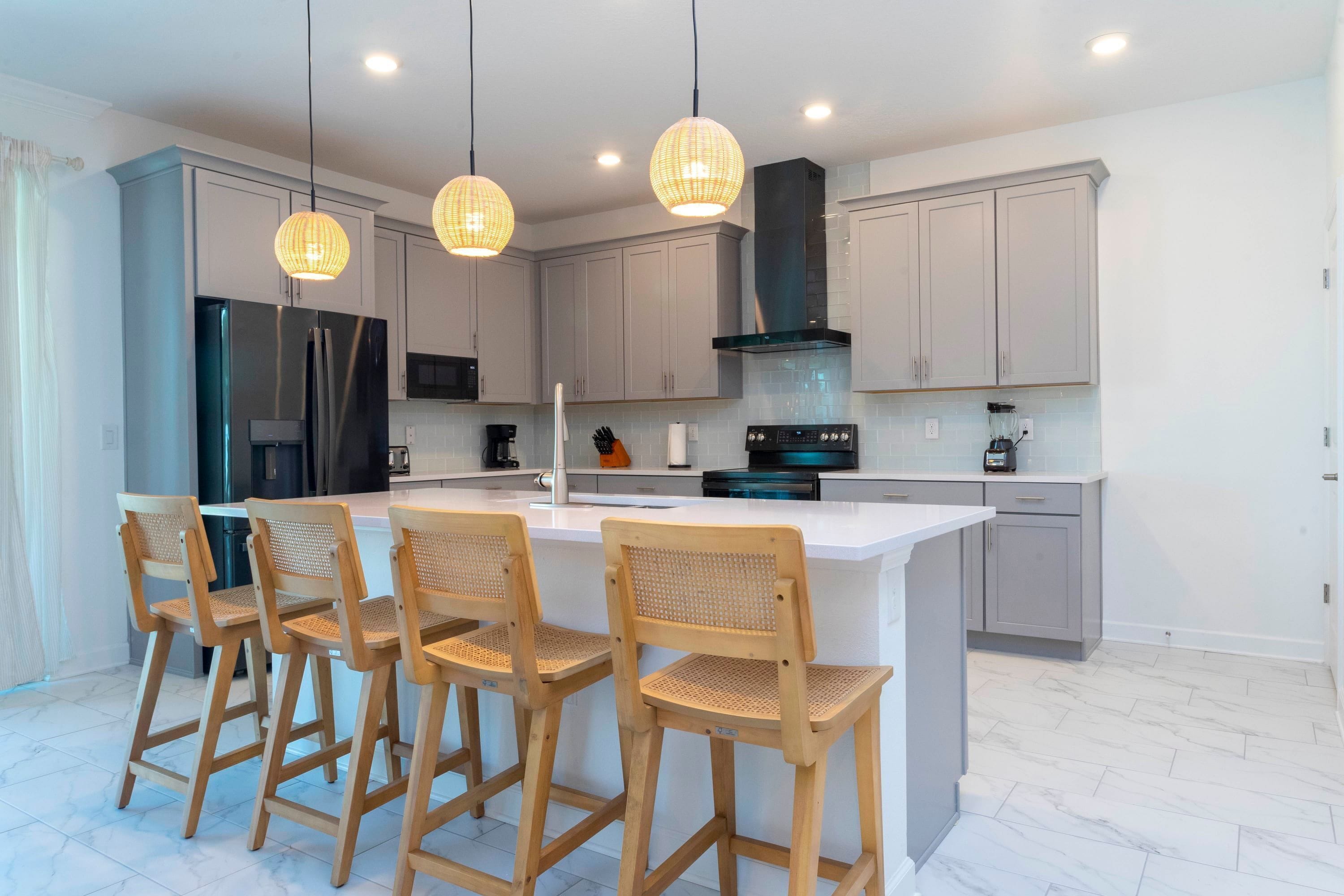 Uma cozinha moderna com uma ilha central, banquetas e iluminação pendente.