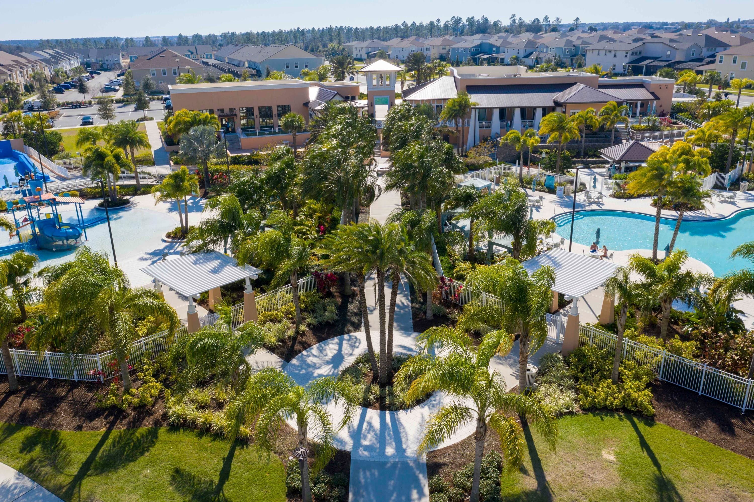 Resort com piscina central, palmeiras e um tobogã.