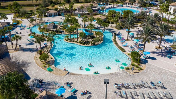 Resort com várias piscinas, palmeiras e áreas de descanso.