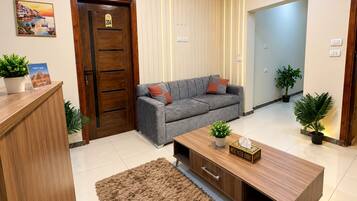 Uma sala de estar moderna com um sofá cinzento, um aparador de madeira e uma mesa de centro.