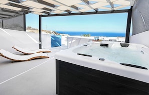 Uma banheira de hidromassagem moderna ao ar livre, com vista desobstruída para o oceano.