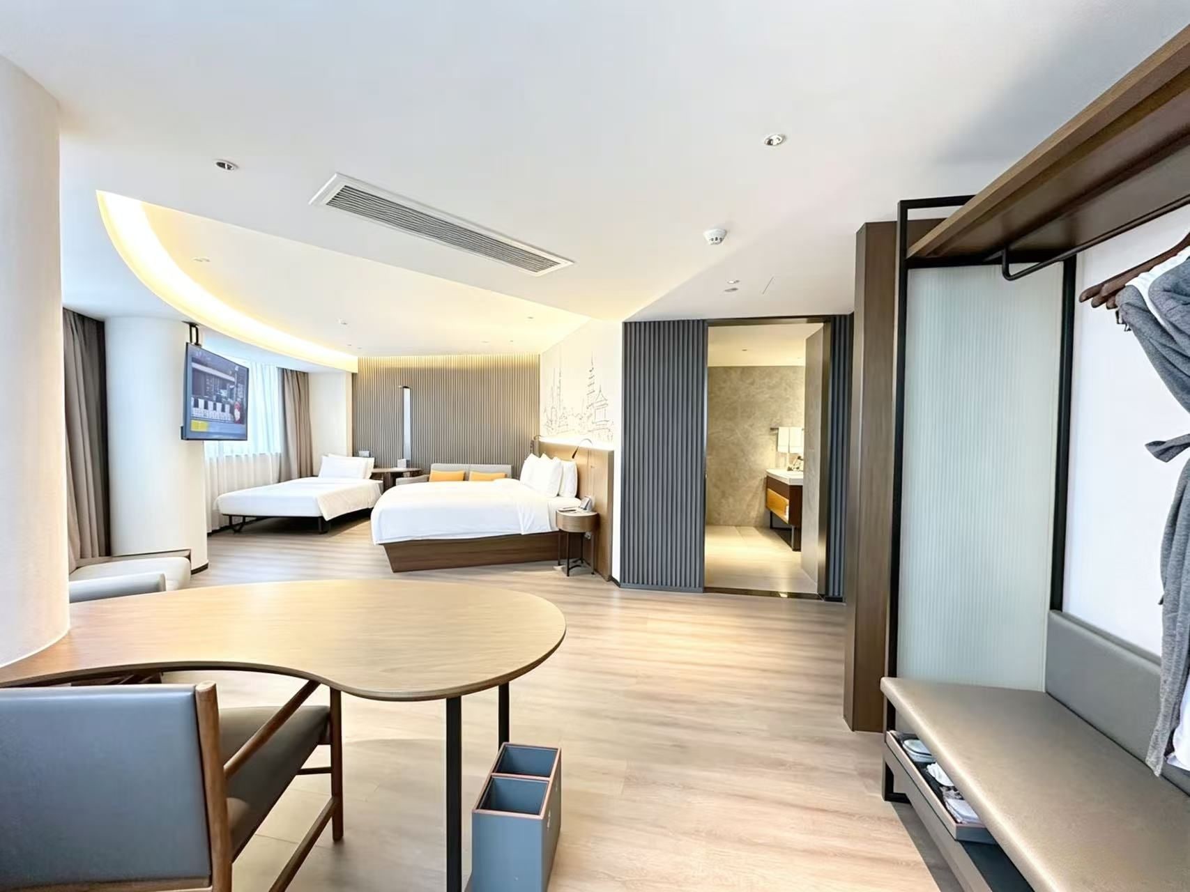 Quarto de hotel com cama, mesas de cabeceira, escrivaninha e área de estar.