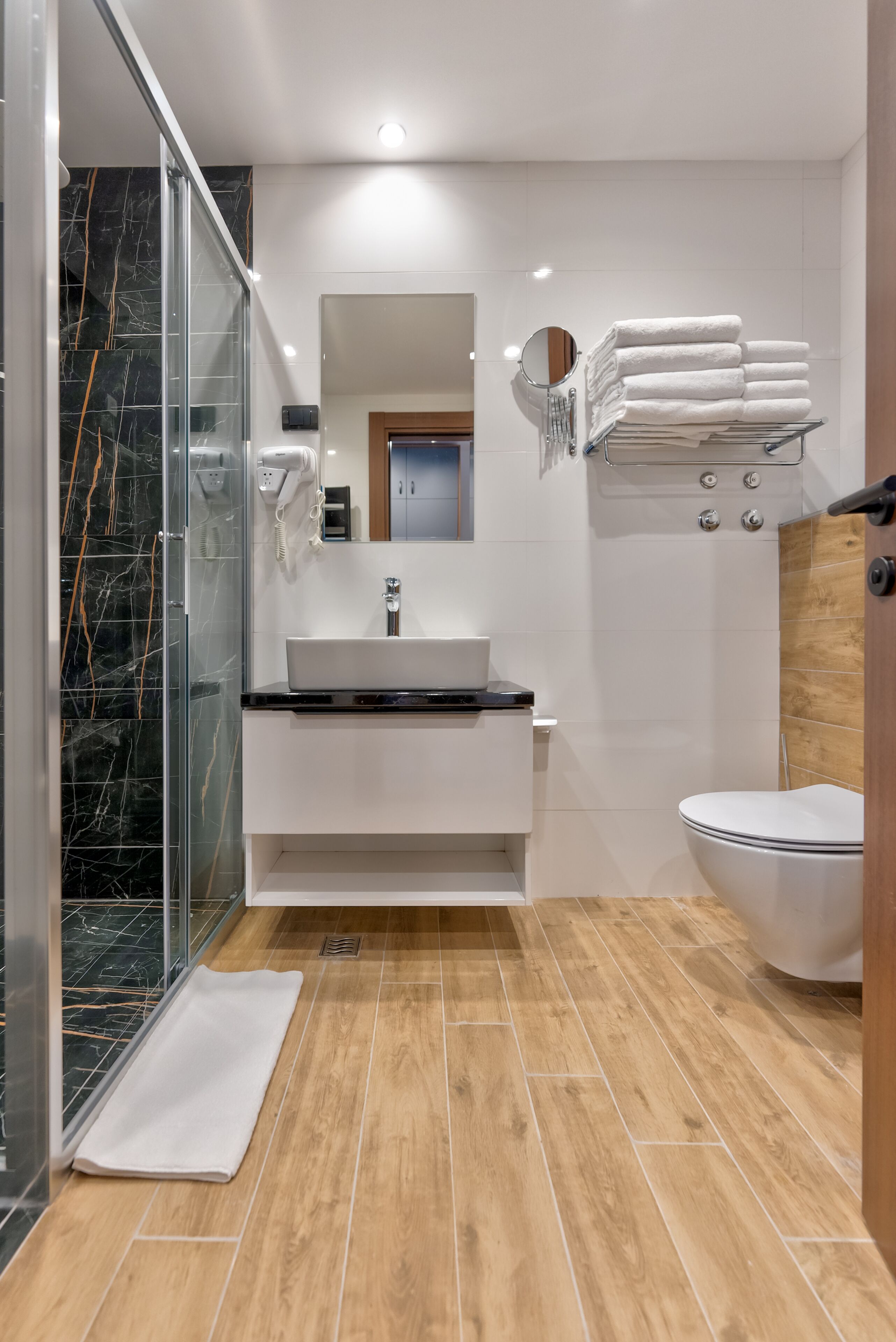 Uma casa de banho moderna com cabine de duche em vidro, lavatório com espelho e sanita.