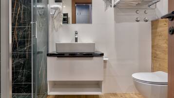 Uma casa de banho moderna com cabine de duche em vidro, lavatório com espelho e sanita.