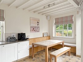 Uma cozinha com um banco de madeira, uma mesa e uma janela com vista para o verde.