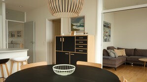 Uma área de refeições moderna com uma mesa redonda, cadeiras, toalha de mesa preta e uma tigela decorativa branca.