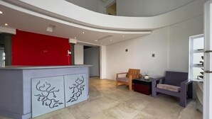 Um hall espaçoso com uma receção em arco, uma área de estar com cadeiras e uma escadaria para um andar superior.