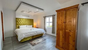 Quarto com cama, guarda-roupa de madeira, janela com cortinas e luminária no teto.