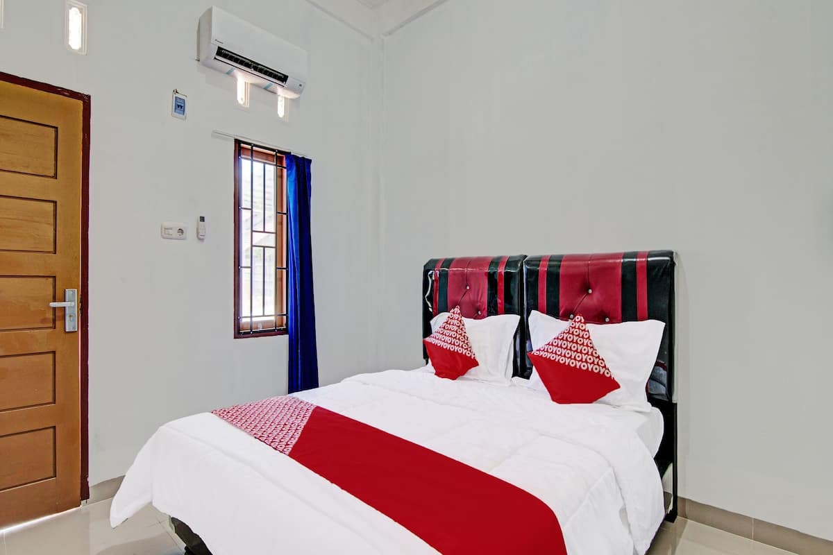 Quarto de hotel com uma cama, uma porta de madeira, ar condicionado e uma janela com cortinas azuis.