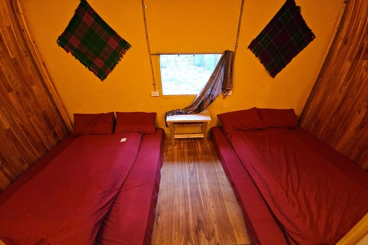 Quarto compacto com duas camas de solteiro, piso de madeira e uma pequena janela com vista.