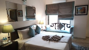Quarto de hotel com cama, mesas de cabeceira, luminária, janela com cortinas, espelho e um quadro na parede.
