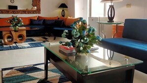 Uma sala de estar com sofá, mesa de centro, espelho e abajur.