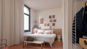 Quarto com cama, mesa de cabeceira, abajur e obra de arte na parede.